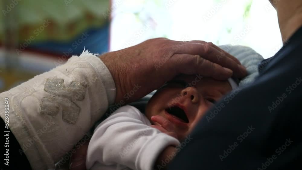 the hand of a blessing priest on the head of a baby in the Orthodox ...