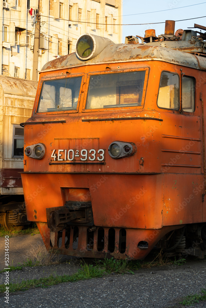Abandoned decommissioned orange soviet locomotives stand on overgrown ...