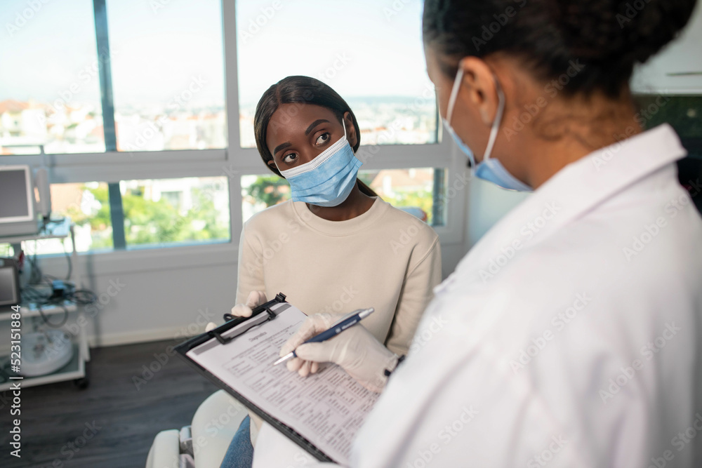 Doctor filling in questionnaire of female patient in clinic. Young ...