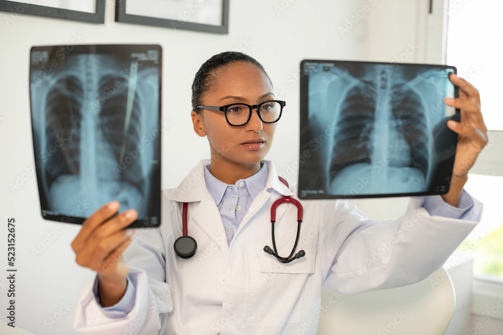 Portrait of confident female doctor examining x-ray pictures in her ...