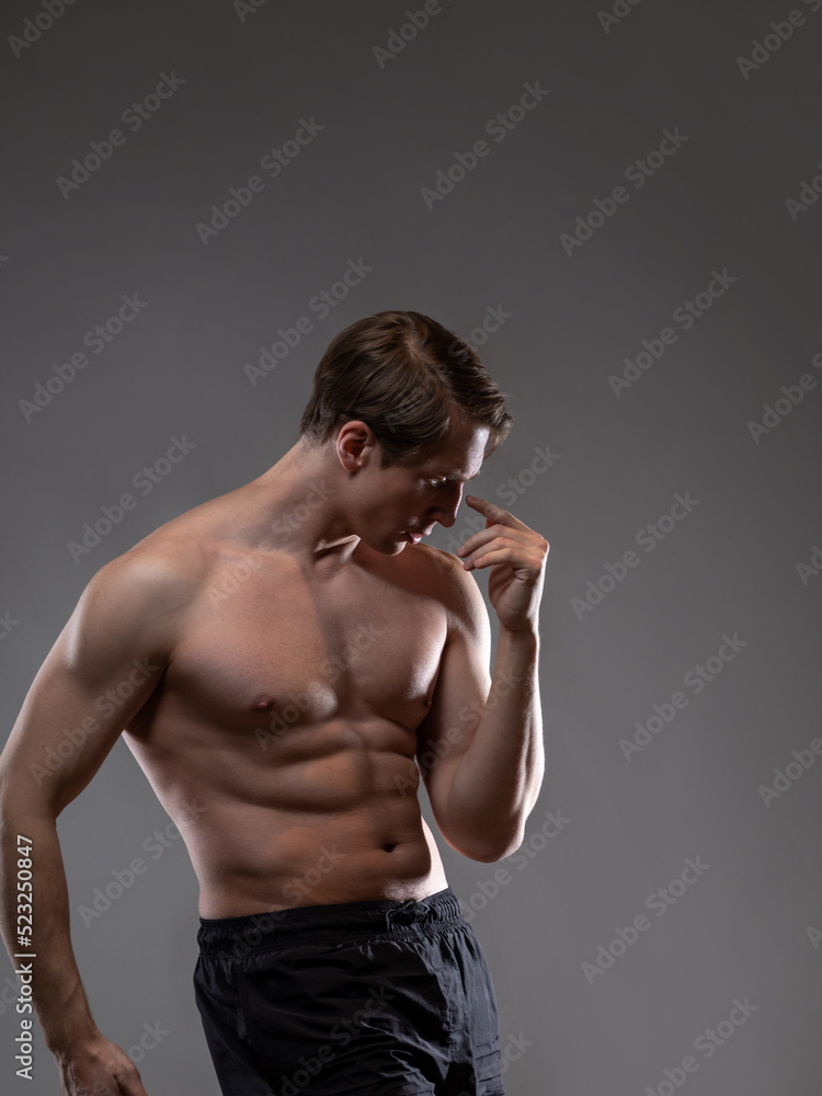 A muscular man expressively emotionally poses on a gray background. The ...