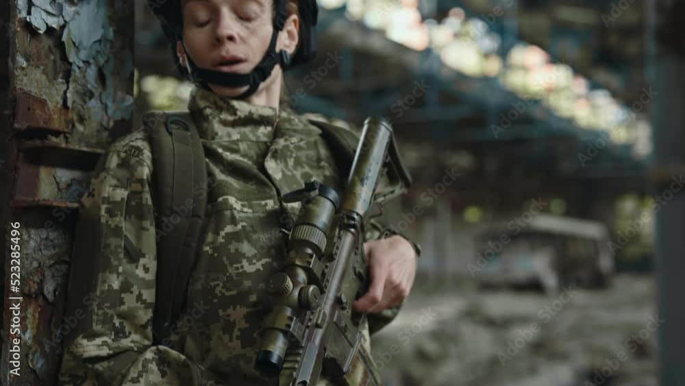 Professional fully equipped female soldier taking cover behind concrete ...