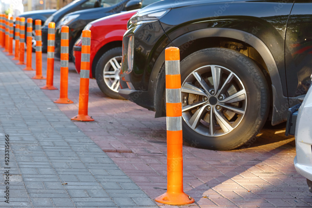 Cars parked in row close to plastic parking barrier, orange anti ...