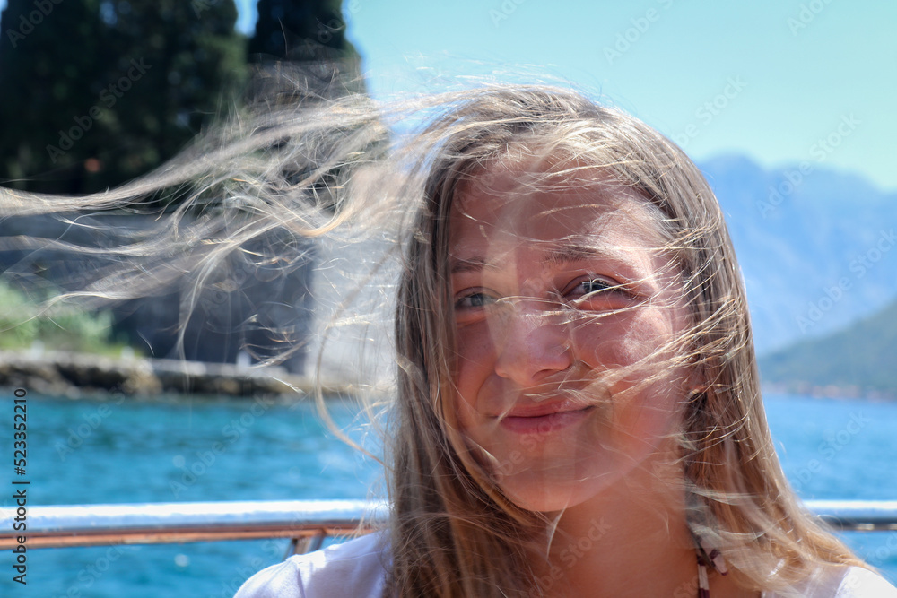 A beautiful girl with wind blowing hair across her face while traveling ...