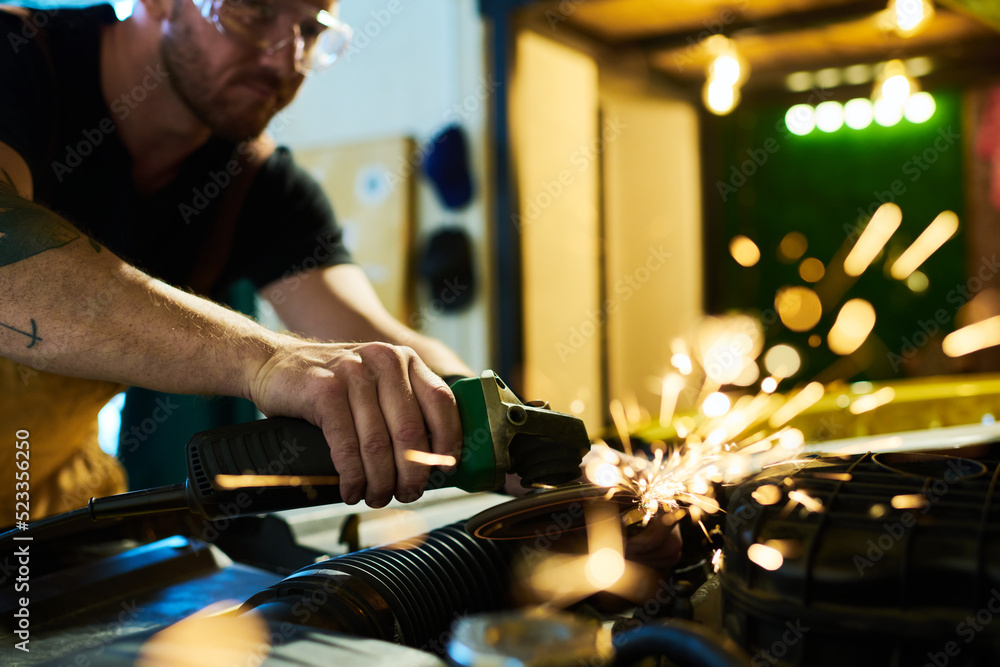 Young maintenance service worker with electric handtool grinding ...