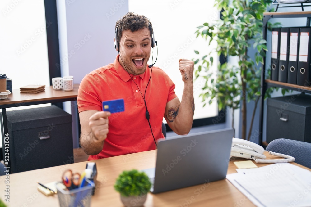 Young hispanic man wearing call center agent headset holding credit ...