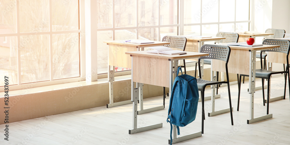 Interior of modern empty classroom with hanging backpack on desk Stock ...