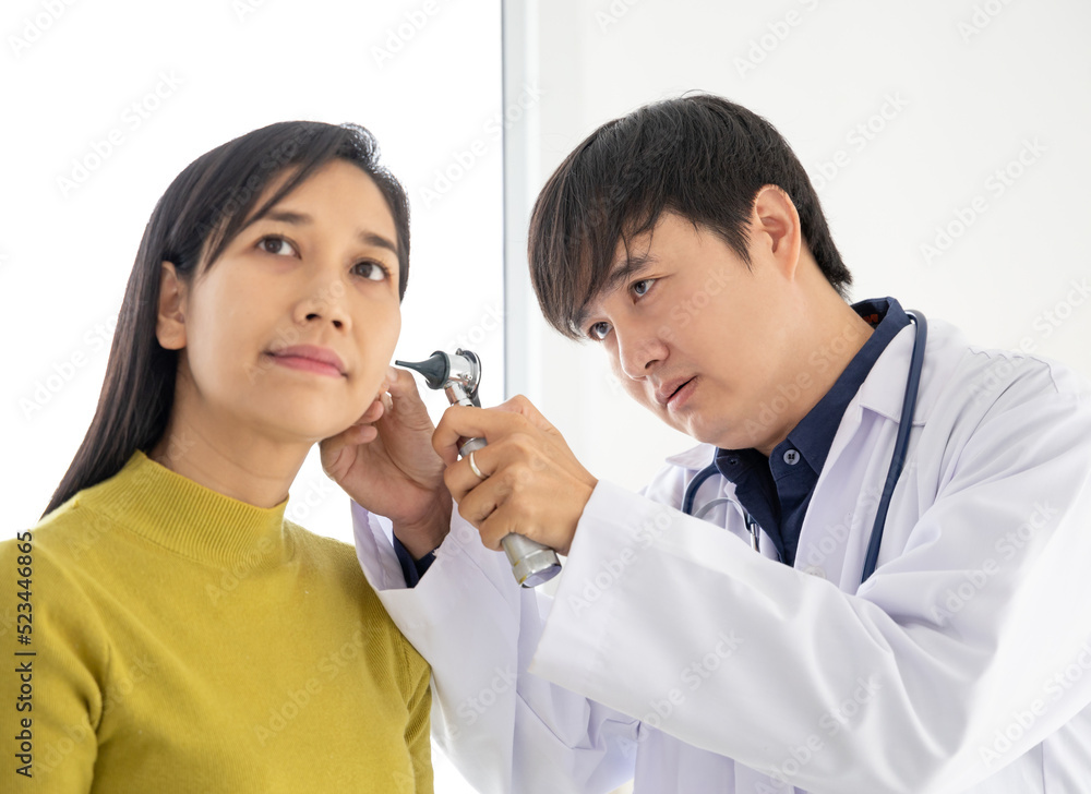 Audiologist examining young female patient ear using otoscope Stock ...