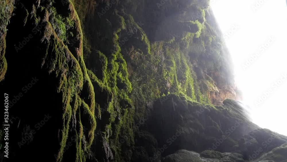 Cave behind waterfall. Beautiful rock wall covered on moss and lichen ...