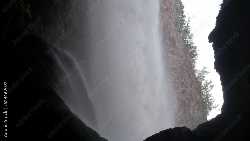 Waterfall drop from inside a cave. Water plunge between rocks and cliff ...