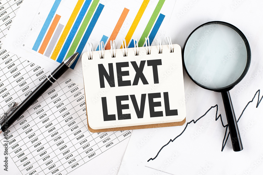 NEXT LEVEL text on notebook on the graph background with pen and ...