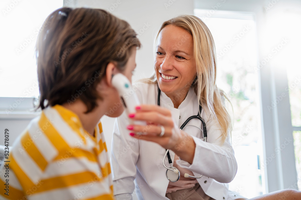 Smiling female doctor examining boy taking his temperature Stock Photo ...