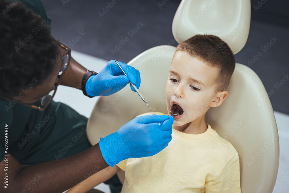 Dentist doing regular dental check-up to little boy. Little cute ...