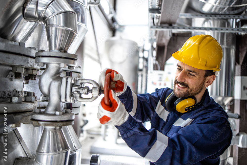 Refinery factory worker closing valve on gas pipeline in petrochemical ...