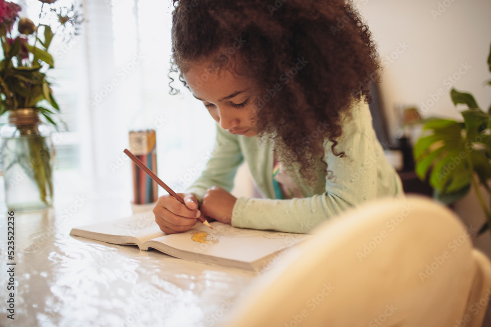 Girl coloring in coloring book at table Stock Photo | Adobe Stock