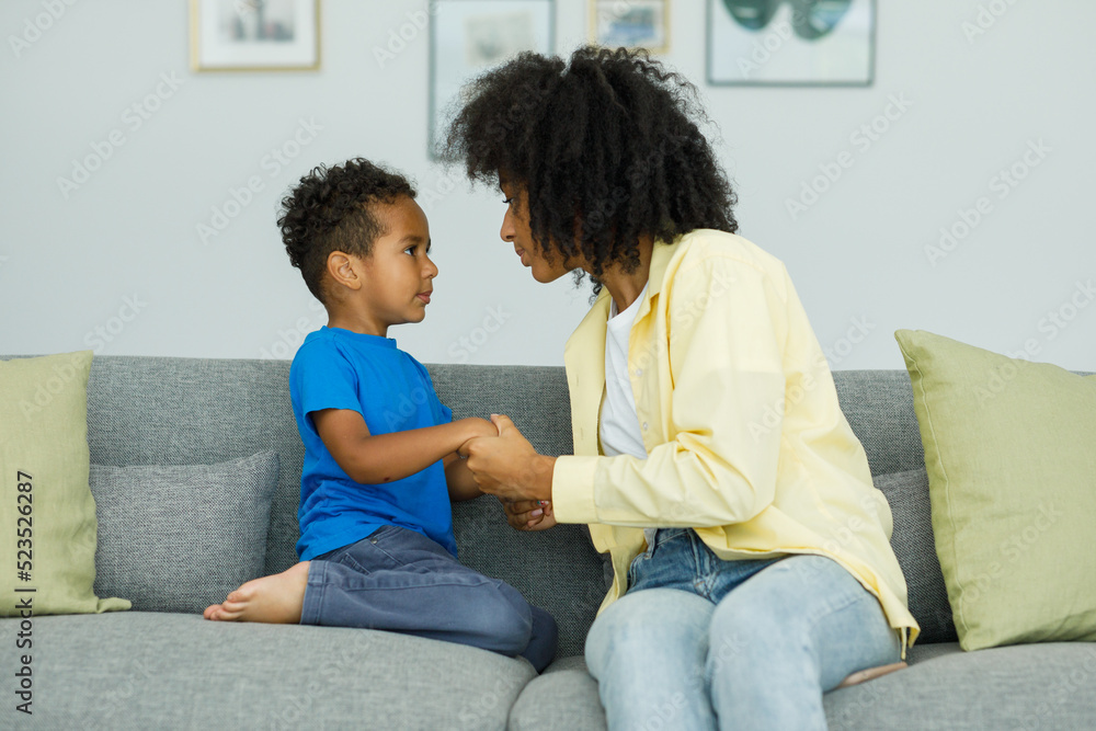 Angry young mother arguing with little son who is misbehaving by being ...