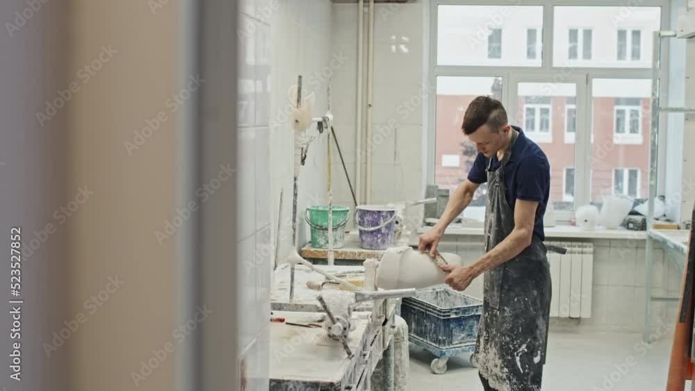 Professional craftsperson standing at workbench forming plaster cast ...