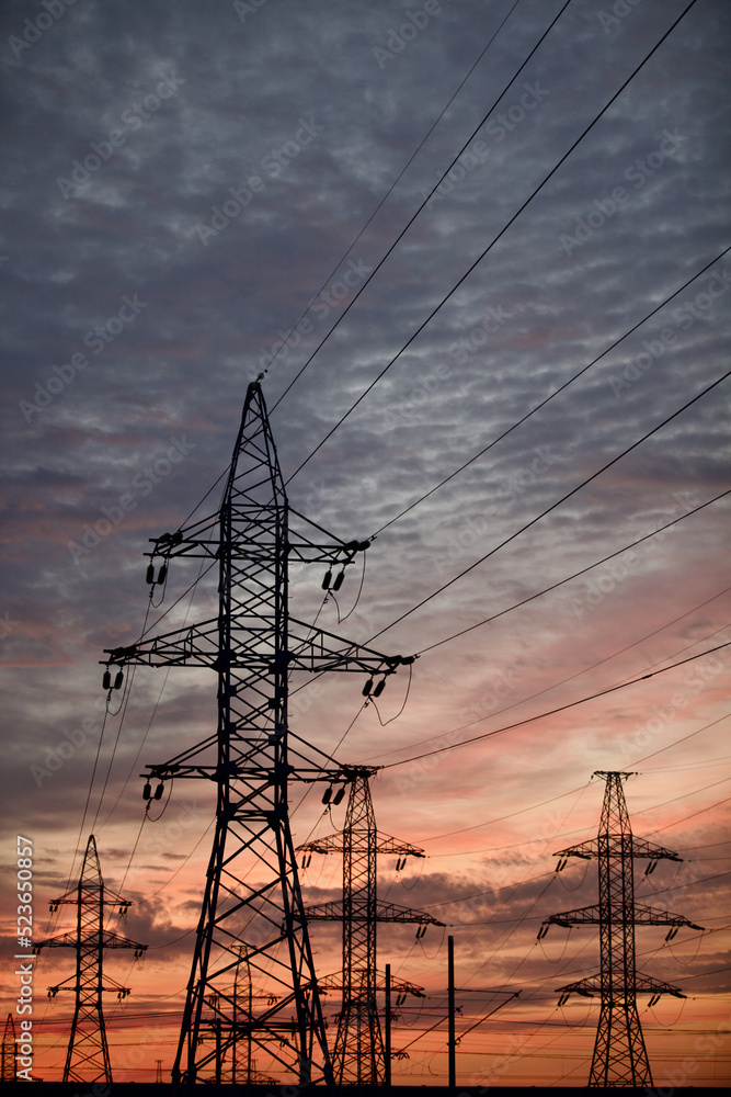 High voltage power lines pylons and electrical cables on a sunset sky ...