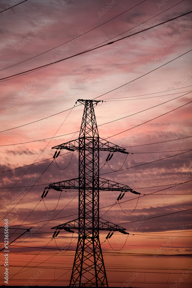 High voltage power lines pylons and electrical cables on a sunset sky ...