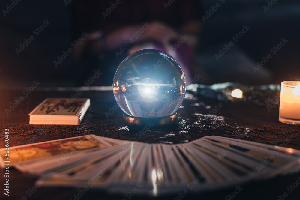 Fortune teller with illuminated crystal ball and tarot cards to ...