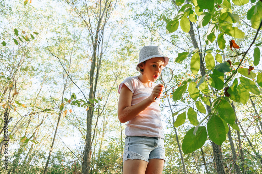little child naturalist botanist with a magnifying glass is surprised ...