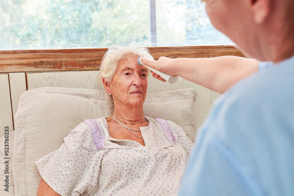 Nurse measures fever in an old woman Stock Photo | Adobe Stock