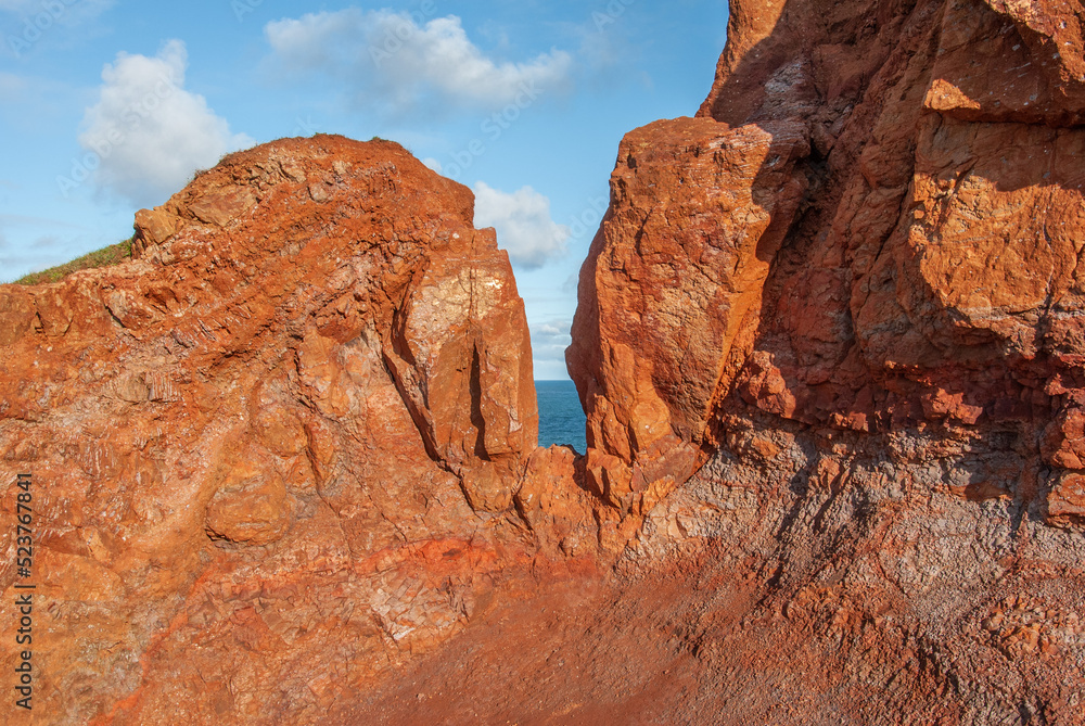 Red laterite rock at Giants Causeway on the Antrim Coast with a view of ...