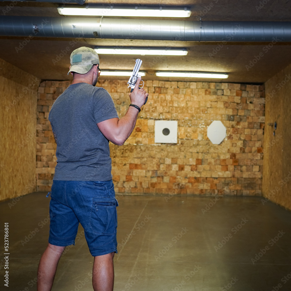 A man with a revolver in a shooting range trains to shoot at a target ...