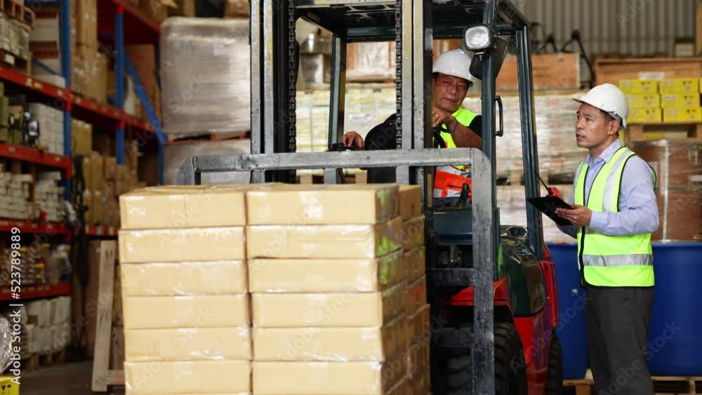 Warehouse staff driving forklift operator moving boxes in industrial ...