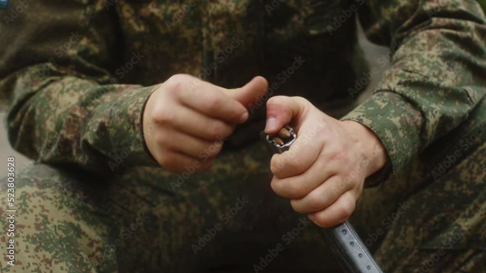 A Russian soldier in camouflage uniform is loading a machine gun ...