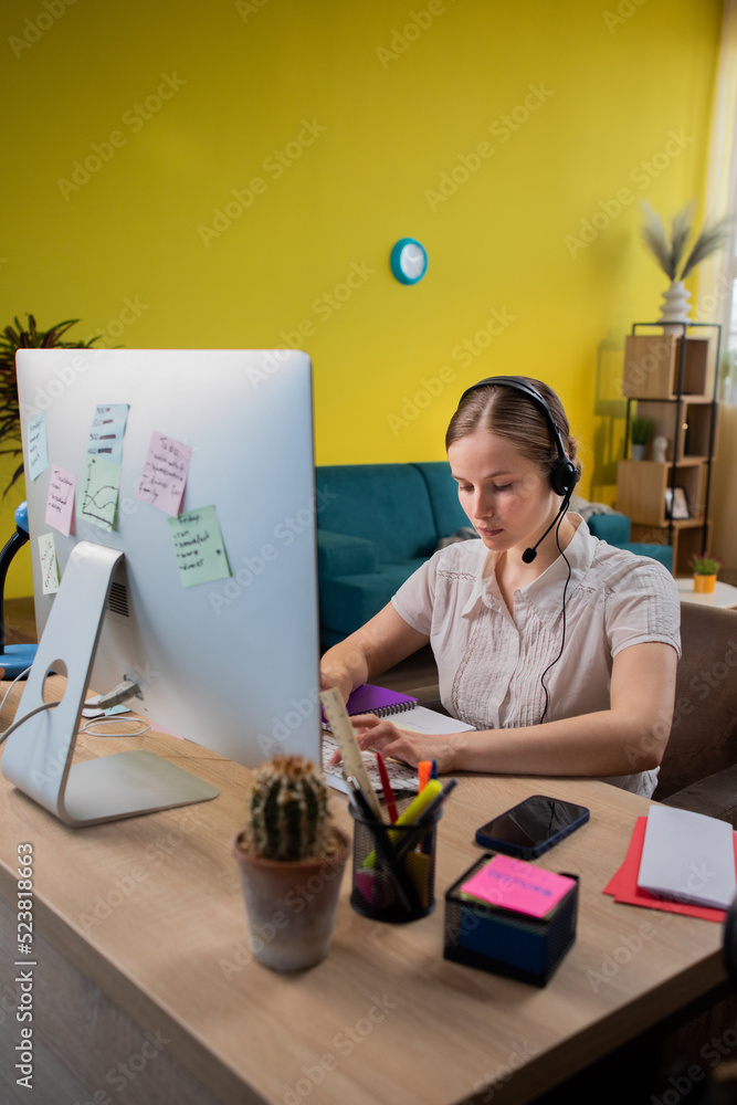 Portrait view of focused young woman in headset with microphone sitting ...