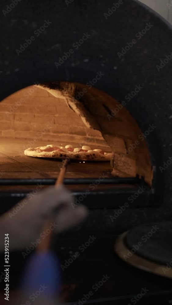 Vidéo Stock Vertical view of a chef rotating the freshly baked pizza in ...