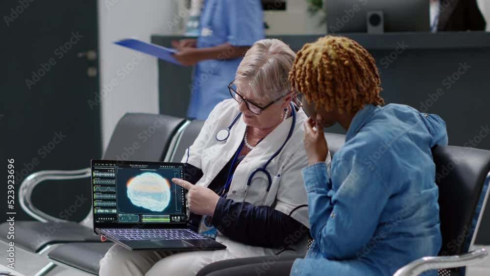 Doctor and patient analyzing human brain scan on laptop, looking at ...
