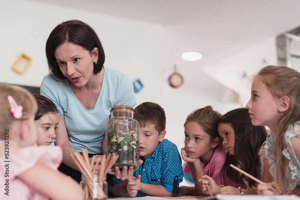 Female Teacher with kids in biology class at elementary school ...