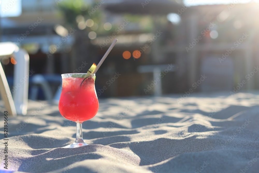 Red cocktail in the sand. Red cocktail with ice cubes, a slice of lime ...