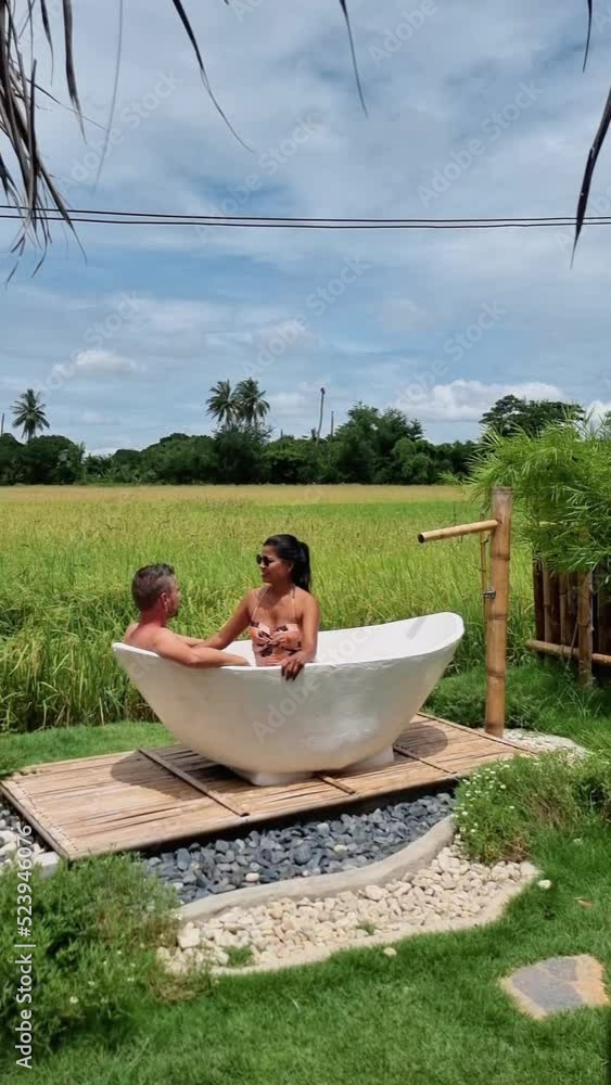 a couple of men and women in a white bathtub outside looking out over a ...