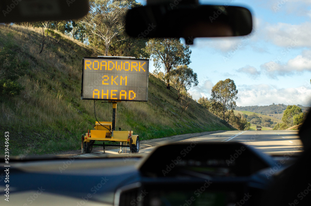 Electronic screen road sign with text .'roadwork 2km ahead' on side of ...