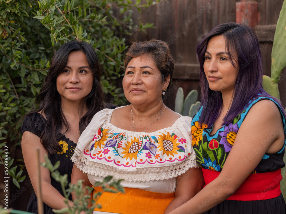 Horizontal image of Indigenous women holding hands in an outdoor garden ...