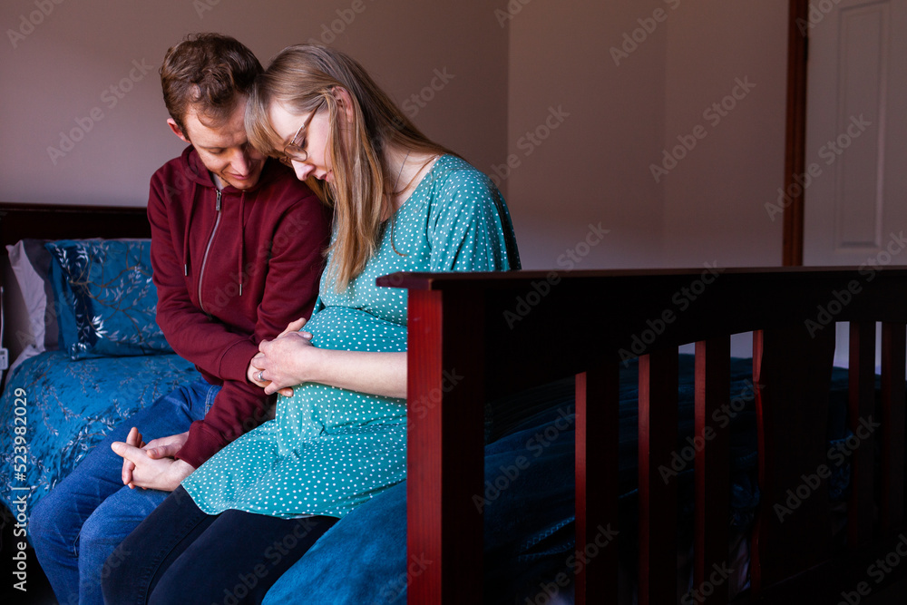 Young christian couple praying together in bedroom for unborn baby ...