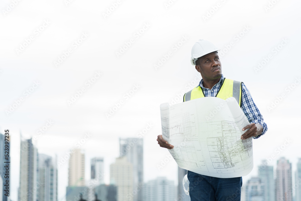 African American male engineer working with building blueprint for ...