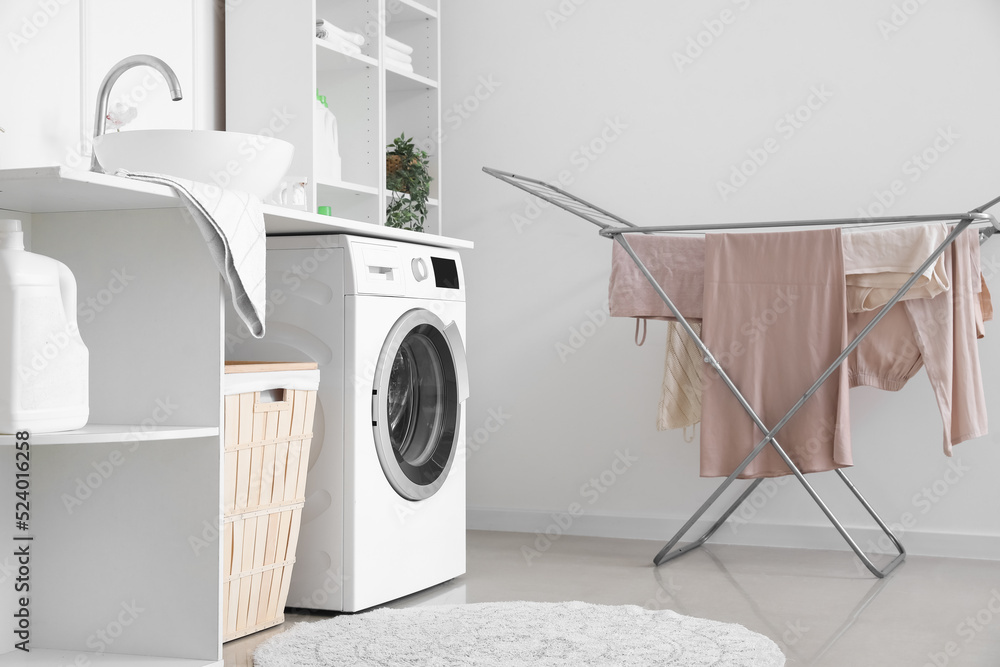 Interior of light laundry room with washing machine, dryer and shelving ...