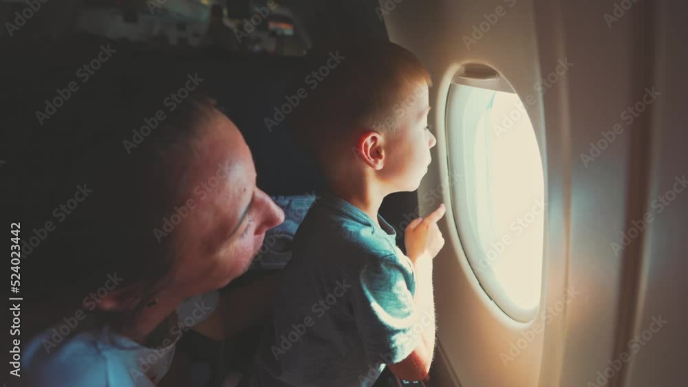 Mom with small baby boy flying on plane. They look out window and boy ...