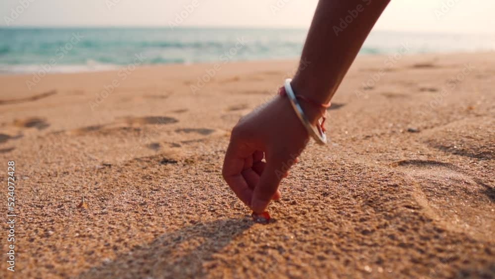 Closeup shot of hand of an Indian man picking up sea shell from the ...