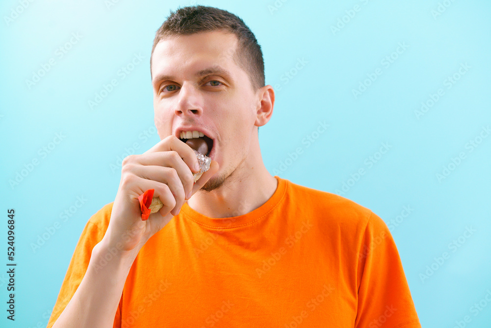 An angry man eating a milk chocolate bar is packaged in the plastic ...