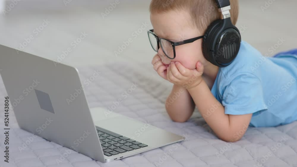 baby child boy in blue clothes lying on floor in headphones watching ...