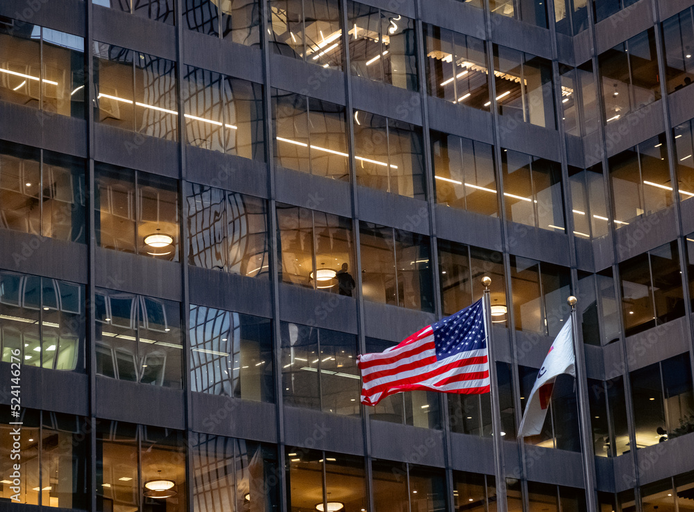 American flag in front of office building with a business man on the ...