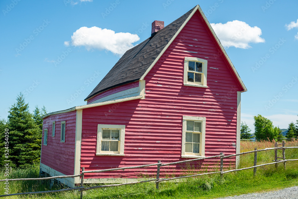 A view of a vintage cottage under blue sky and clouds. The small red ...