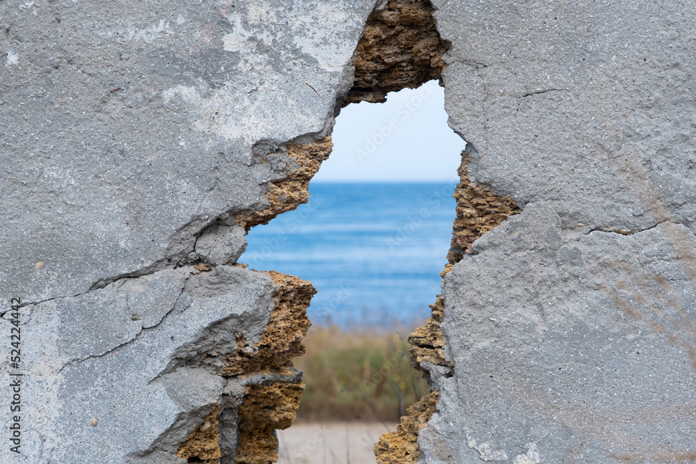 You can see the sea through a hole in the wall. Focus selective on the ...