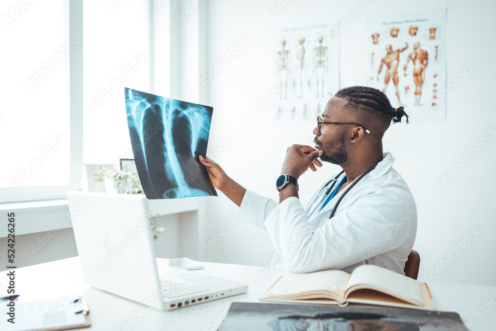 Afrian American adult male doctor looking at x-ray. Doctor examining a ...