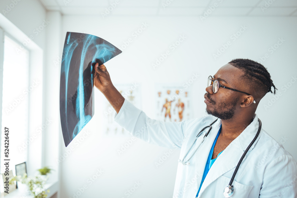 Male radiologist analyzing chest X-ray of an patient at medical clinic ...